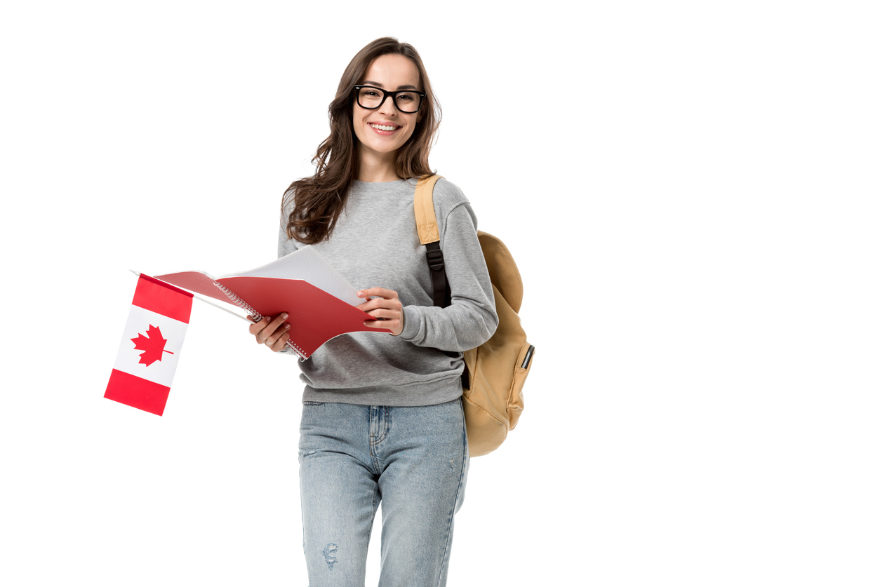 female student looking at camera and holding canadian flag with ...